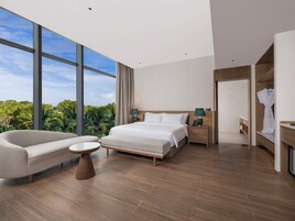 Quarto de hotel moderno com uma cama grande, um sofá, uma mesinha e um closet espaçoso.