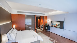 Quarto de hotel moderno com uma cama grande, abajures, uma TV de tela plana, uma escrivaninha com cadeira e um closet espaçoso.