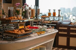 Buffet com diversas opções de comida e vista para a cidade ao fundo.