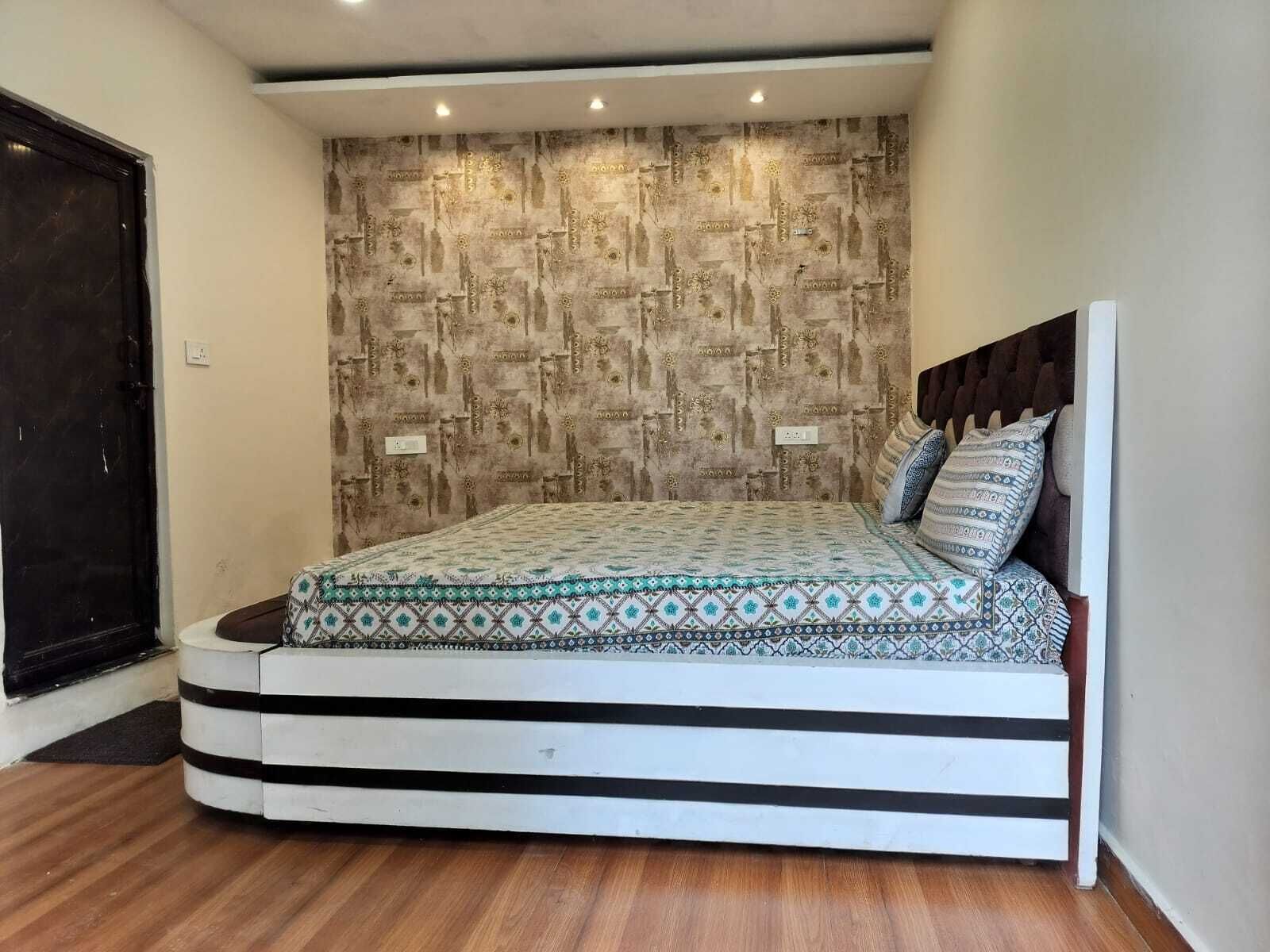 Um quarto com uma cama, parede estampada e chão de madeira.