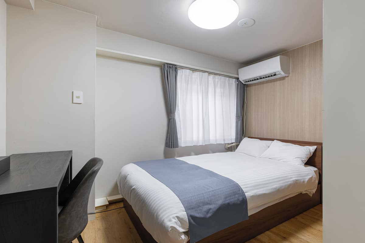 Quarto com cama, escrivaninha e ar condicionado.