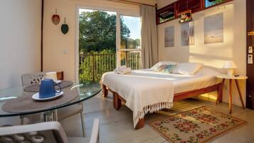 Quarto com cama, mesa de cabeceira e vista para uma varanda.