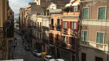 Uma rua estreita ladeada por edifícios altos, alguns com varandas e plantas.