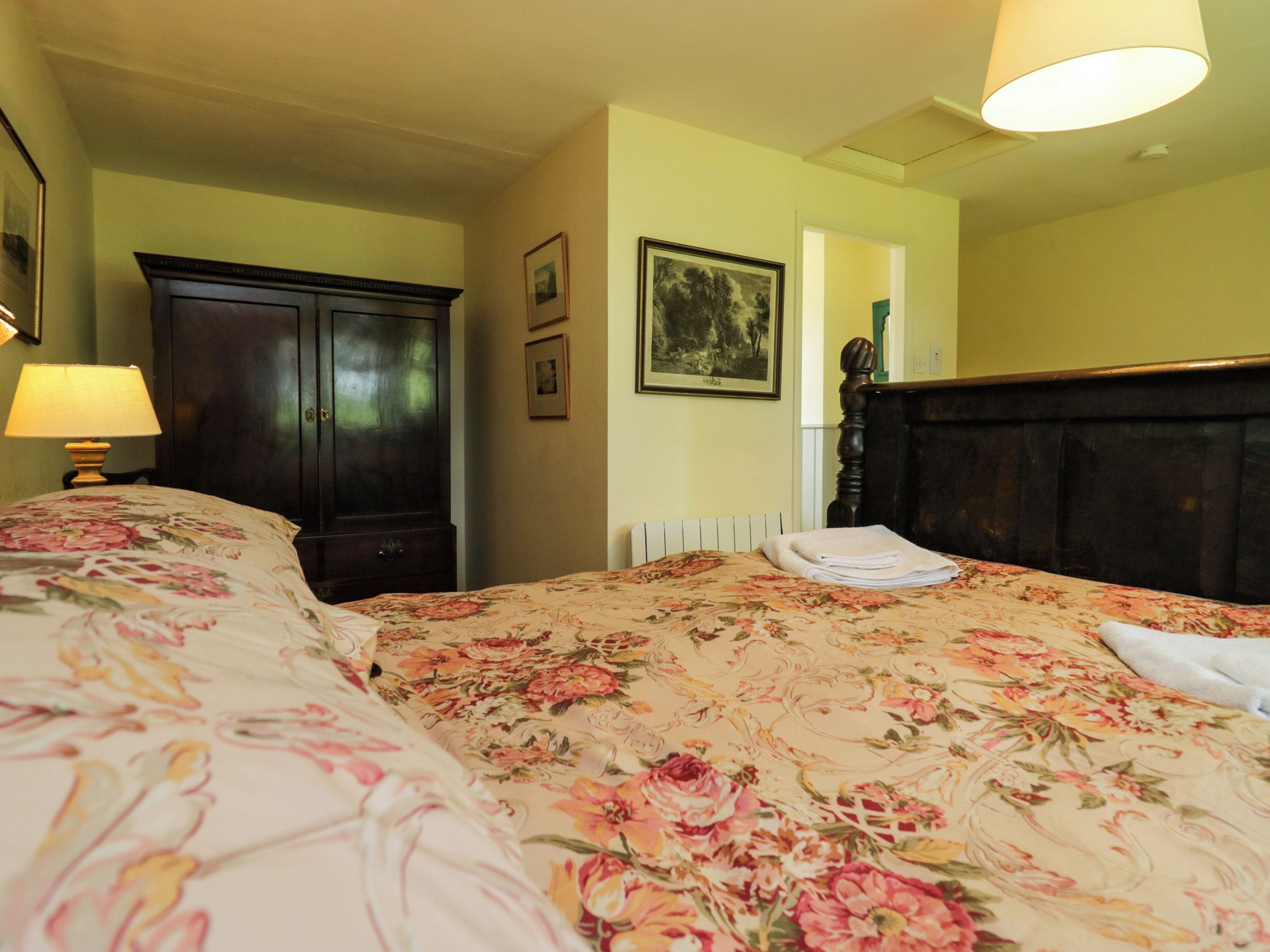 Quarto com cama, cômoda, abajur e um quadro na parede.
