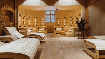 Sala de sauna com bancos e assentos de madeira, parede de tijolos e janela.