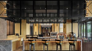 Uma área de bar moderna com bancada de mármore, banquetas e diversos tipos de garrafas.