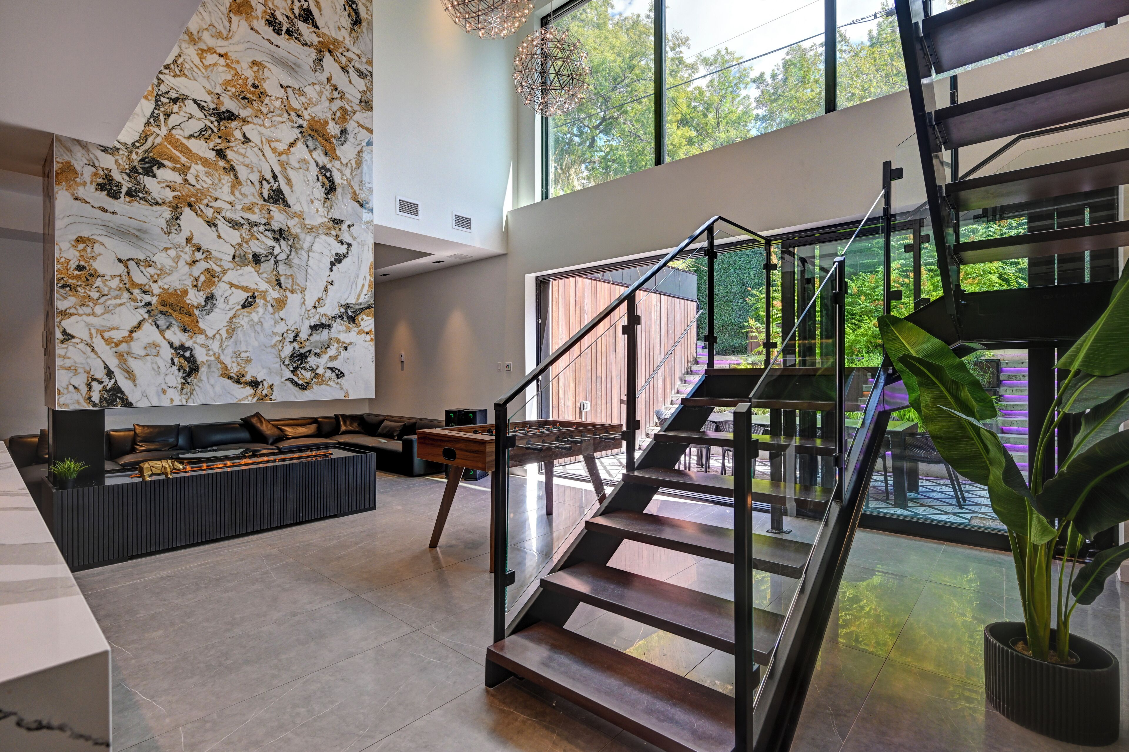 Um interior moderno com escada, uma parede abstrata grande e uma área de estar com mesa de centro.