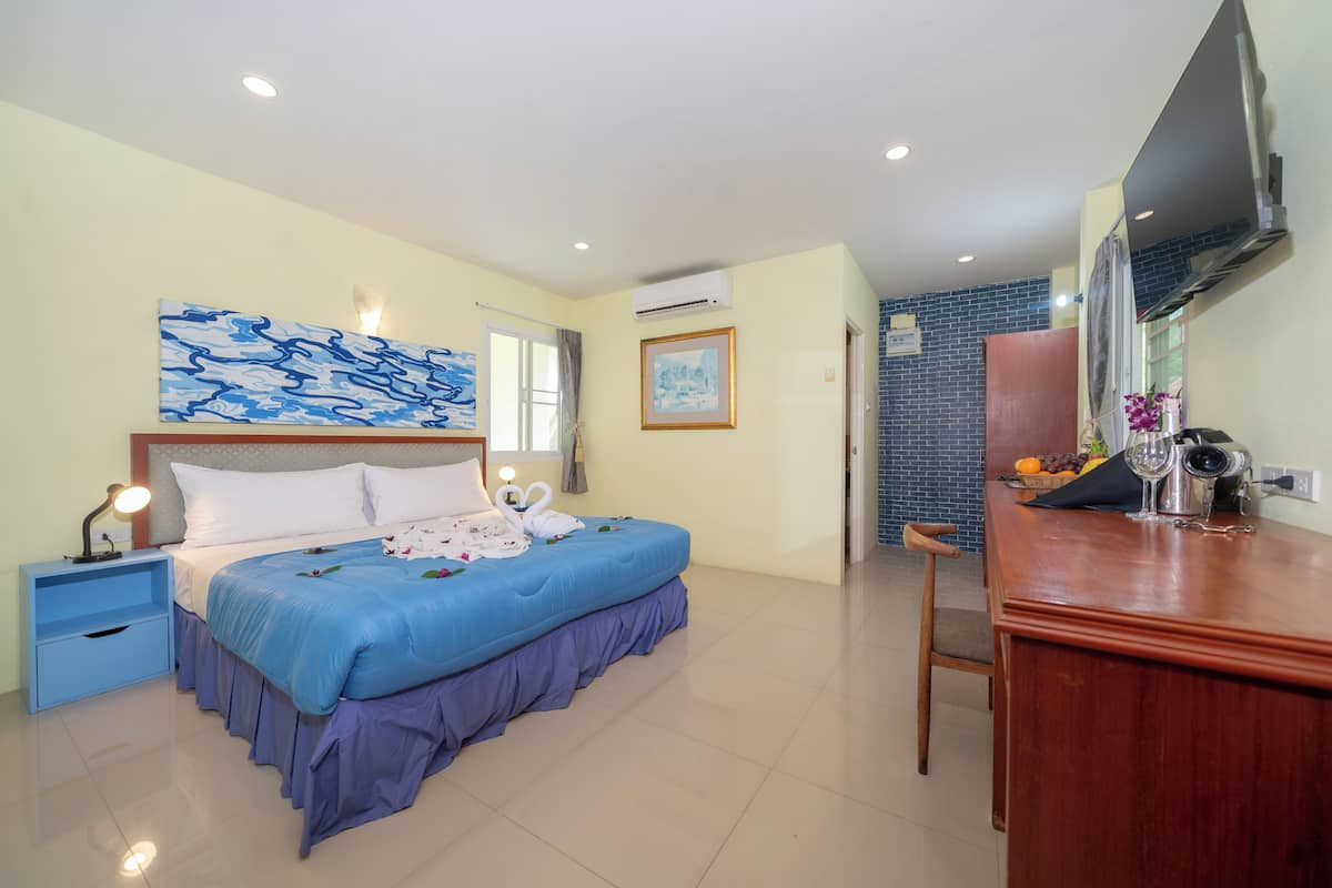 Quarto com cama, mesa de cabeceira e área de trabalho com cadeira.