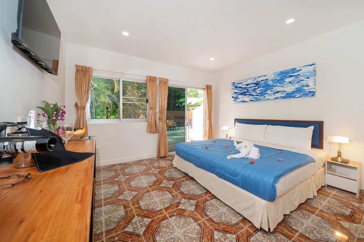 Quarto de hotel com cama, escrivaninha, televisão e janela com cortinas.