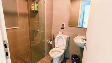 Uma casa de banho com cabine de duche em vidro, sanita e lavatório.