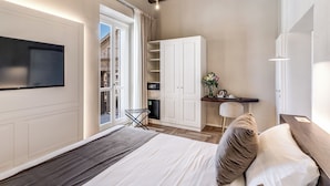 Um quarto moderno com cama, televisão, escrivaninha e armário.