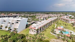 Um resort com vários edifícios, piscina e vista para o oceano.