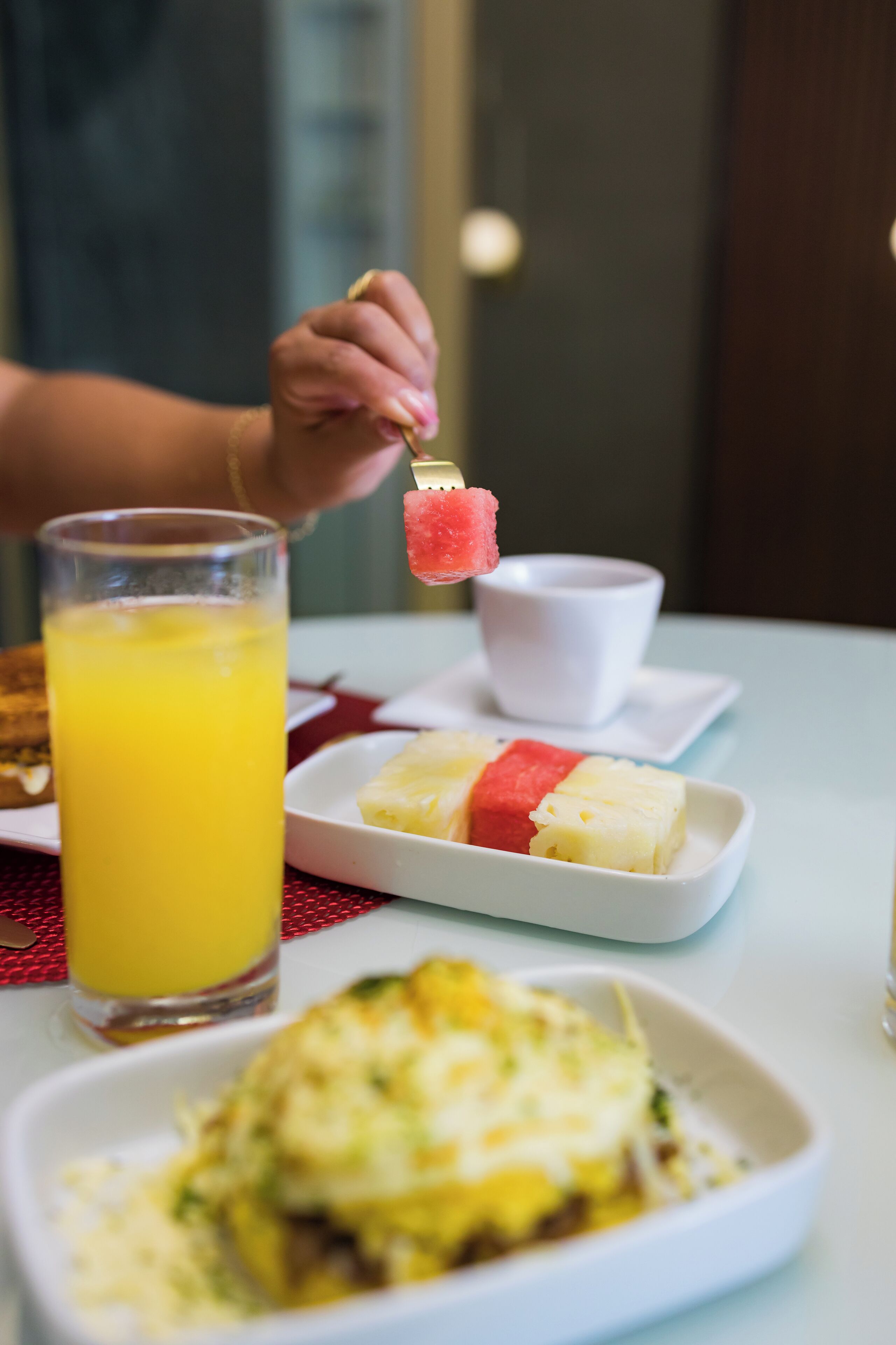 Uma mesa de café da manhã com um copo de suco de laranja, um prato de comida e uma xícara de café.