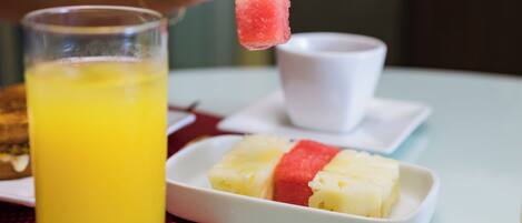 Uma mesa de café da manhã com um copo de suco de laranja, um prato de comida e uma xícara de café.
