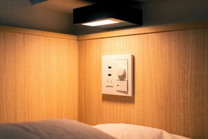 Quarto de hotel com parede de madeira, termostato embutido e uma cama.