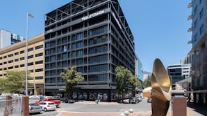 Um edifício de vários andares com design arquitetônico moderno, com varandas e grandes janelas.