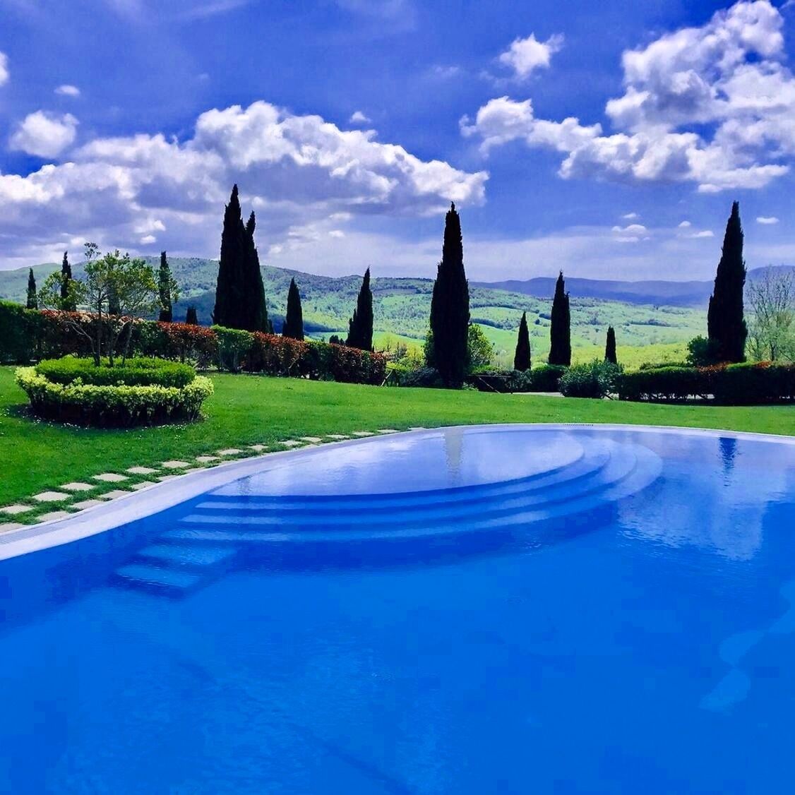 Piscina sob um céu azul límpido e colinas ao longe.