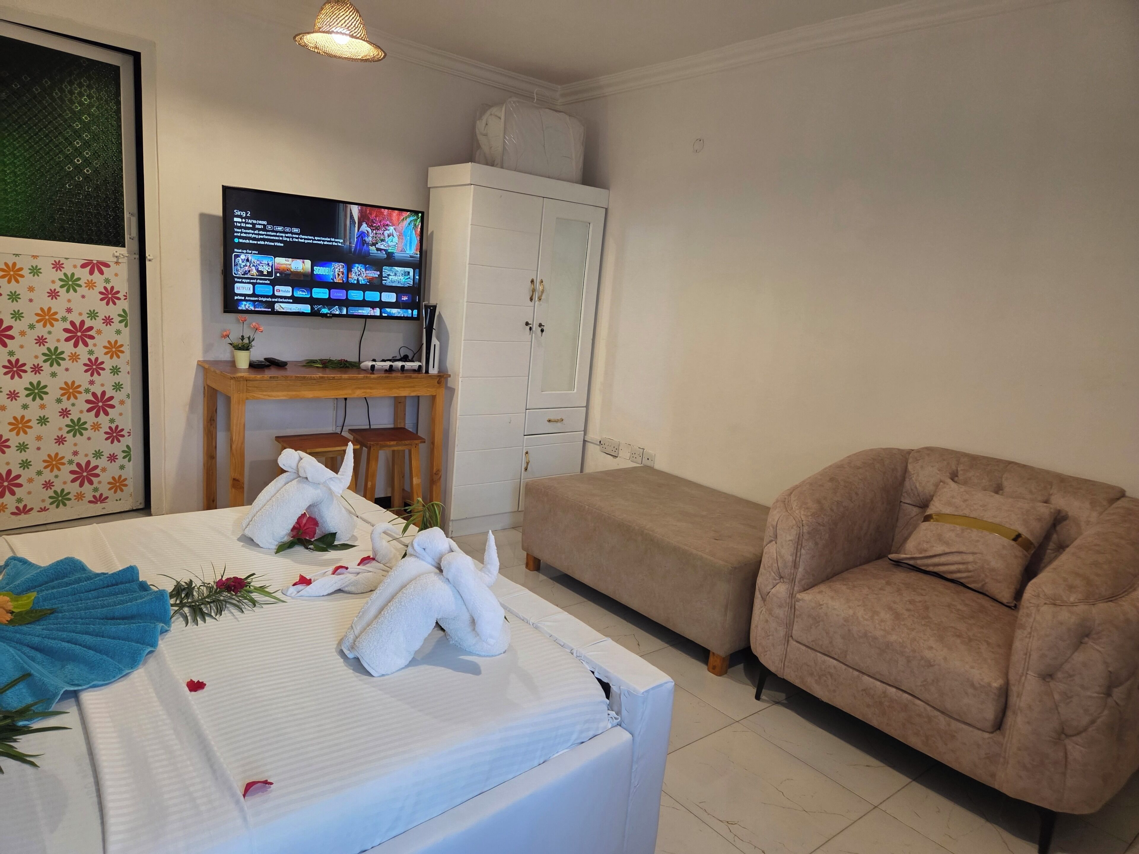 Quarto de hotel com cama, sofá, televisão e um armário.