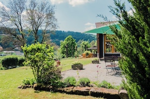 Uma área de estar coberta ao ar livre, com jardineiras de pedra e um deck de madeira.