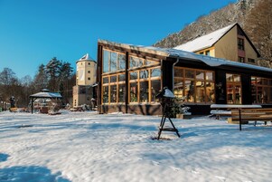 Um edifício com grandes janelas e telhado coberto de neve, em meio a uma paisagem nevada.
