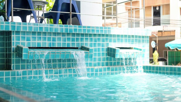 Piscina com borda azulejada e um elemento decorativo aquático.