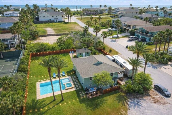 Um bairro residencial com piscina, uma casa com garagem e vista para o mar.