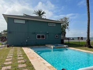 Uma casa de dois andares com piscina no jardim da frente.
