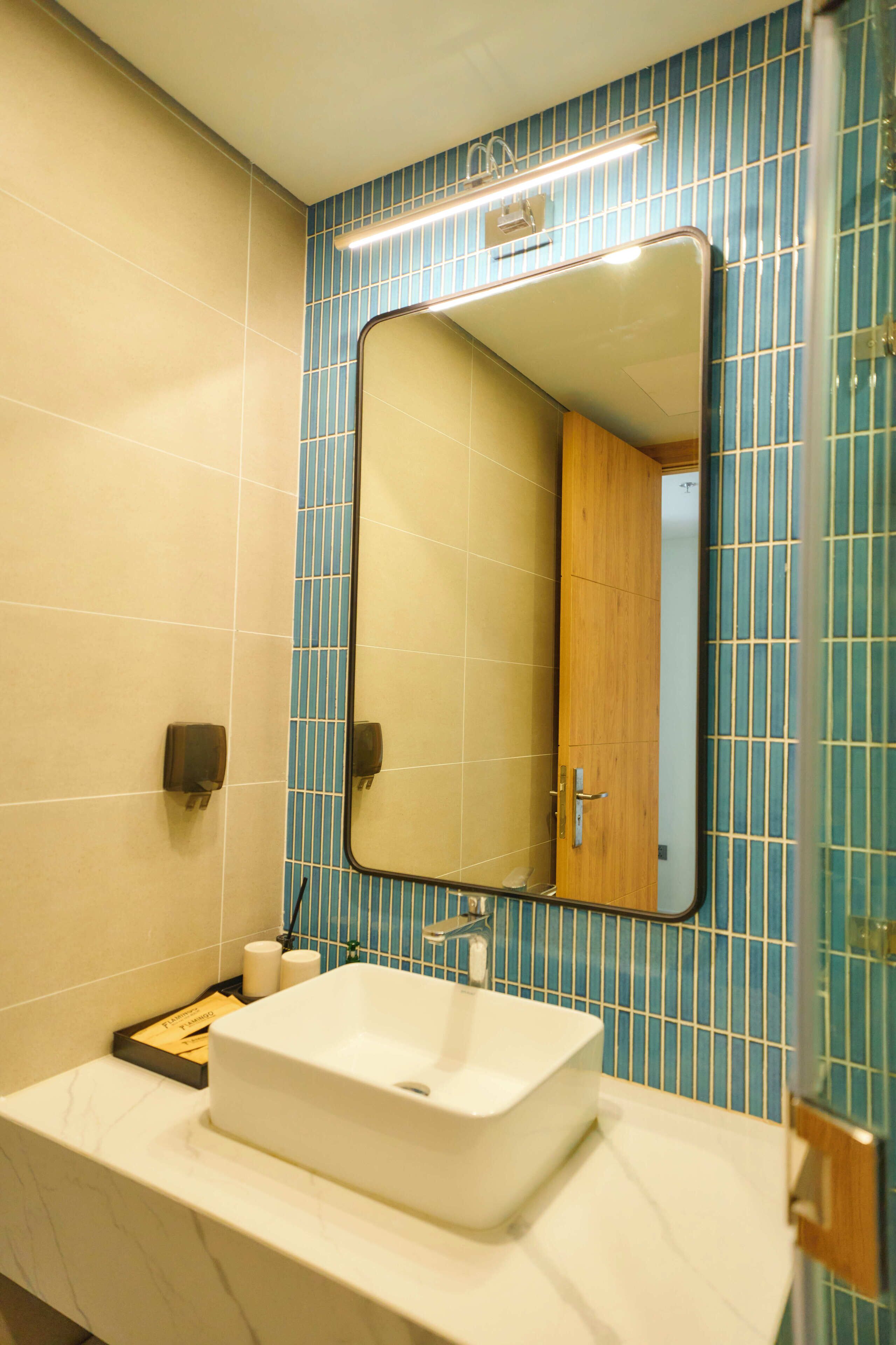 Casa de banho com uma pia branca, um espelho e azulejos azuis.