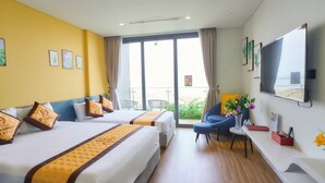 Quarto de hotel com duas camas, uma varanda, televisão e uma pequena mesa com um vaso de flores.