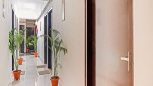 Um corredor com plantas em vasos, uma porta de madeira e piso de azulejos.