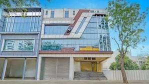 Um hotel moderno com fachada de vidro, entrada destacada com degraus e placa indicando ser um hotel.