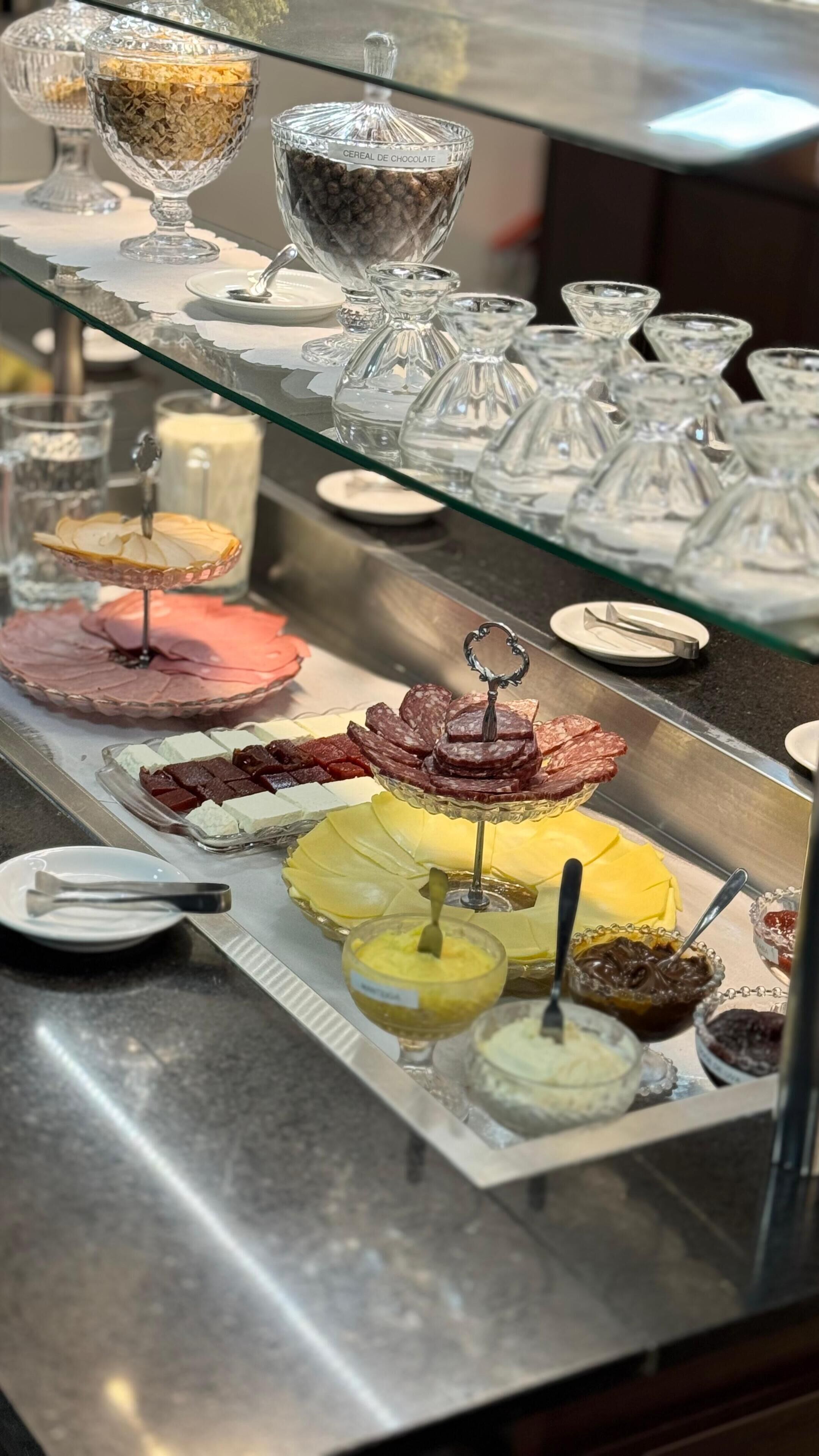 Buffet com diversos alimentos expostos em recipientes de vidro.