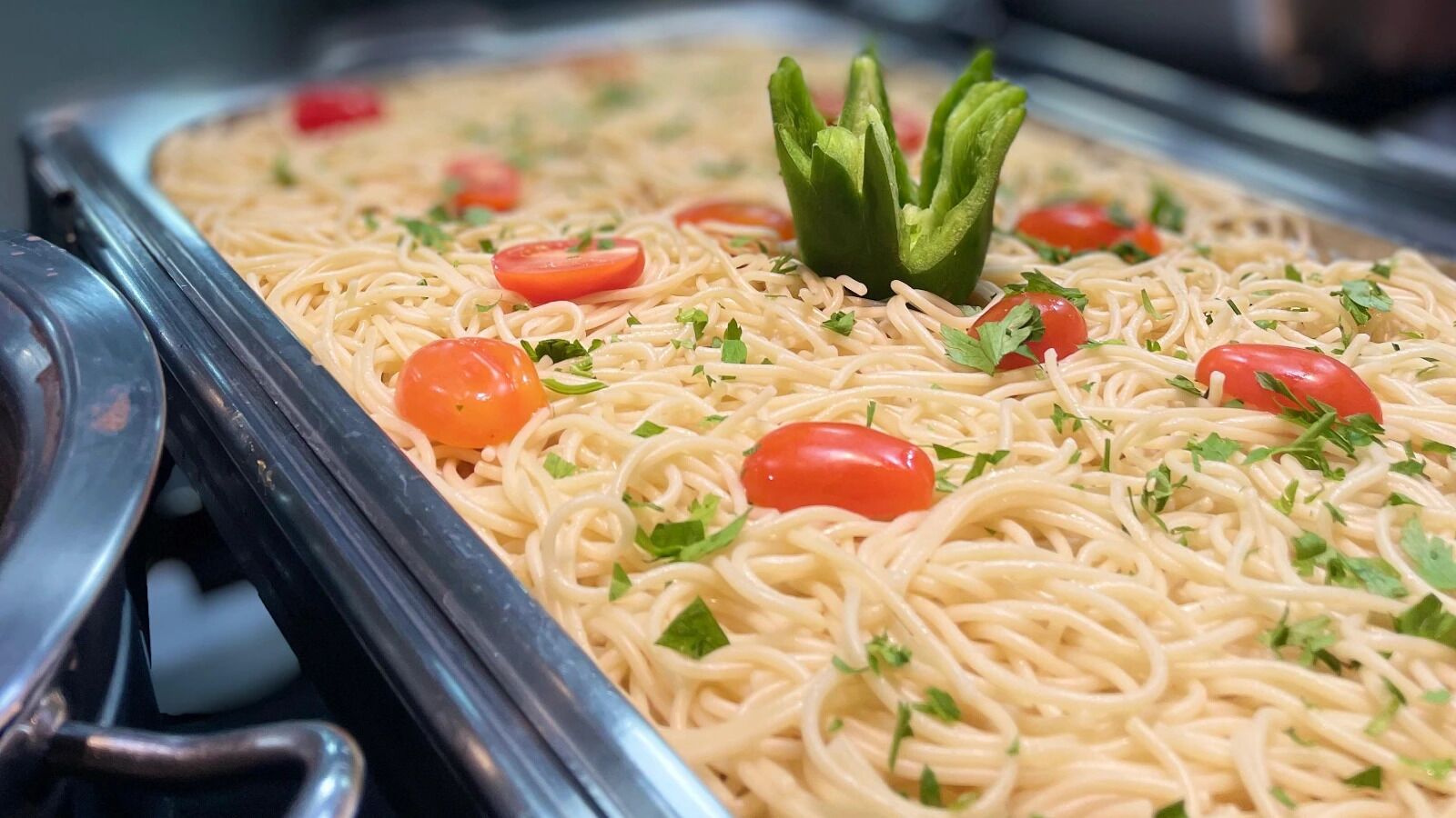 Uma travessa de espaguete com tomates cereja e salsa.