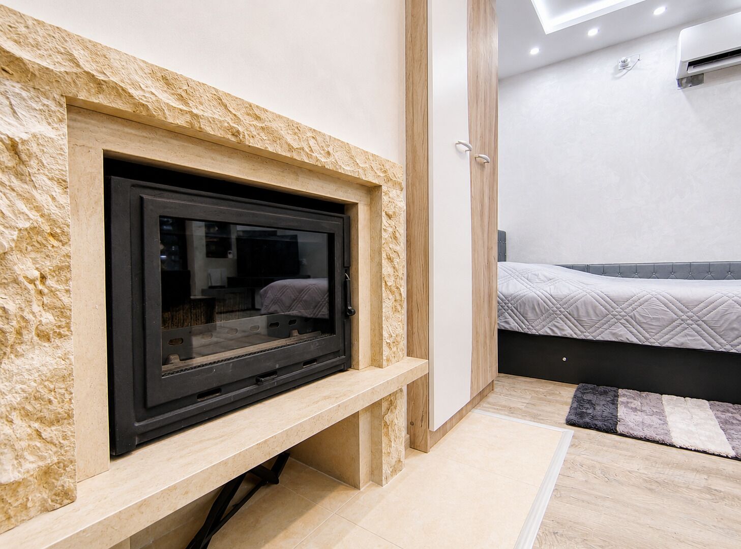 Quarto moderno com lareira embutida, uma cama e uma pequena mesa de cabeceira.