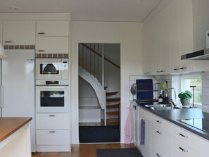 Cozinha moderna com armários brancos, forno embutido e pia de aço inoxidável.
