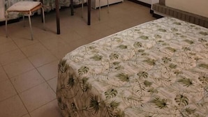 Quarto com cama, escrivaninha, cadeira, estante e um quadro na parede.