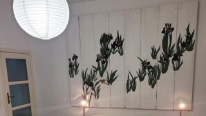 Quarto com cama, luminária fixada na parede e painel decorativo.
