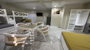 Um espaço compacto com beliche, mesa de jantar com cadeiras, sofá e televisão.