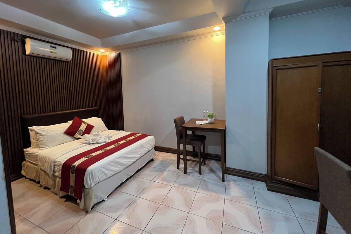Quarto de hotel com uma cama, uma mesa e um guarda-roupa.