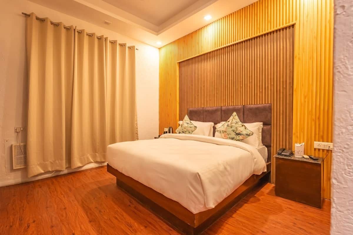 Quarto com cama grande, painel de parede em madeira e mesa de cabeceira com telefone.