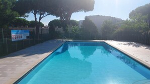 Uma piscina retangular com borda azulejada, rodeada por um calçadão pavimentado. Há uma placa à esquerda indicando que a piscina é privada e não possui supervisão.