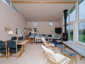 Uma sala de estar aconchegante com sofá, cadeiras, mesa de jantar e lareira.