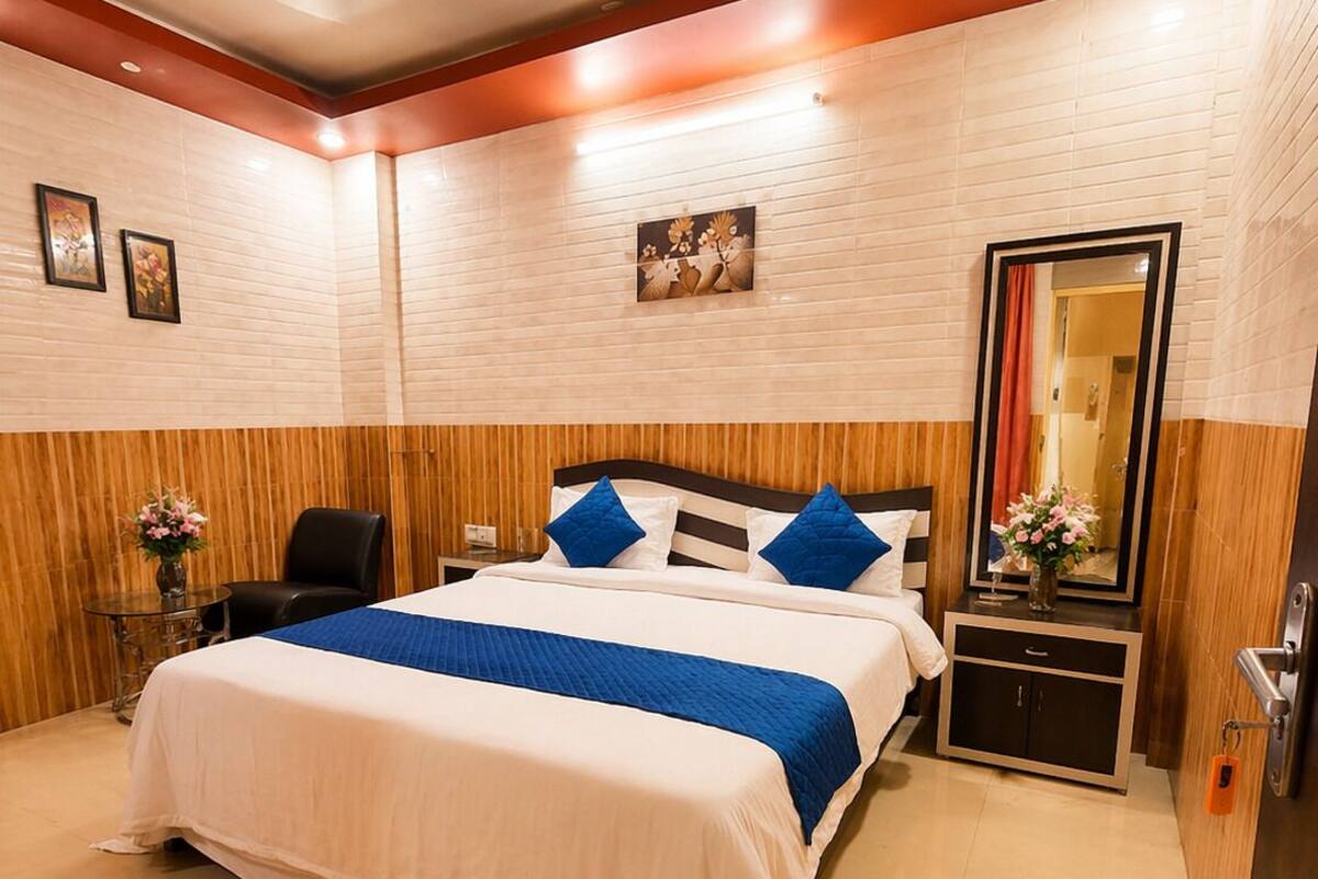 Quarto de hotel com uma cama grande, uma escrivaninha, uma cadeira, um espelho e um pequeno armário.