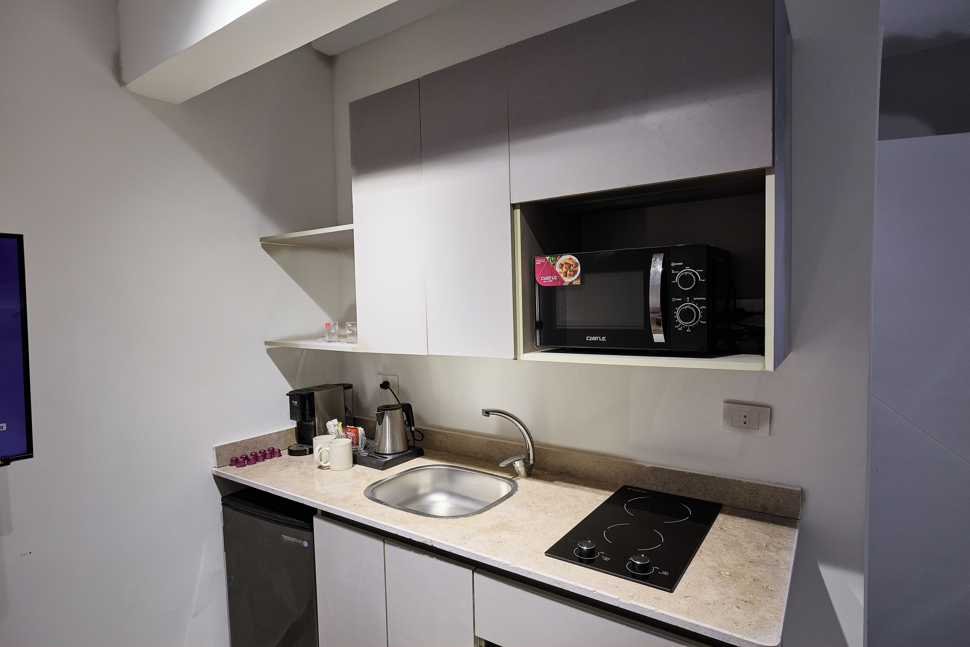 Uma cozinha compacta com micro-ondas, pia e fogão.