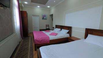 Quarto de hotel com duas camas, televisão, um quadro e guarda-roupa de madeira.