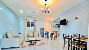 Uma sala de estar com sofá, mesa de centro e área de jantar com cadeiras.