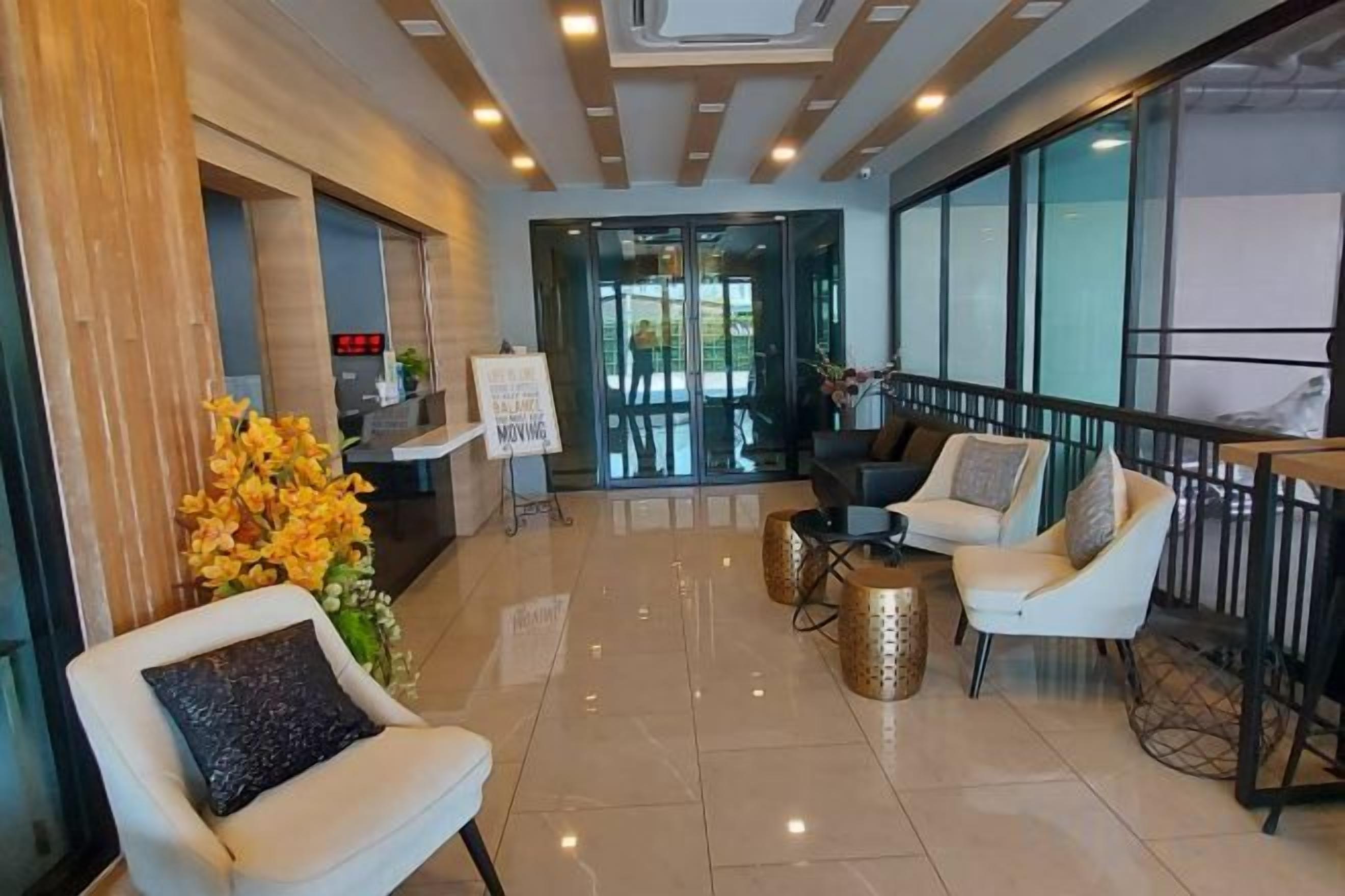 Um saguão de hotel com balcão de recepção, área de estar e grandes janelas.