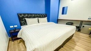 Cama bem arrumada em quarto com paredes azuis e chão de madeira.