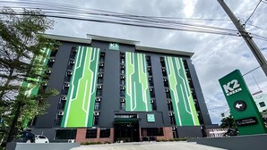 Um edifício moderno com a placa K2, grandes janelas e área de estacionamento na frente.