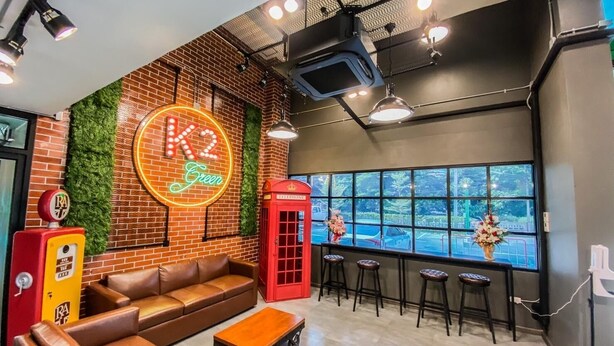 Um espaço de convivência acolhedor, com uma placa de neon, um telefone público vermelho e uma janela grande com vista.
